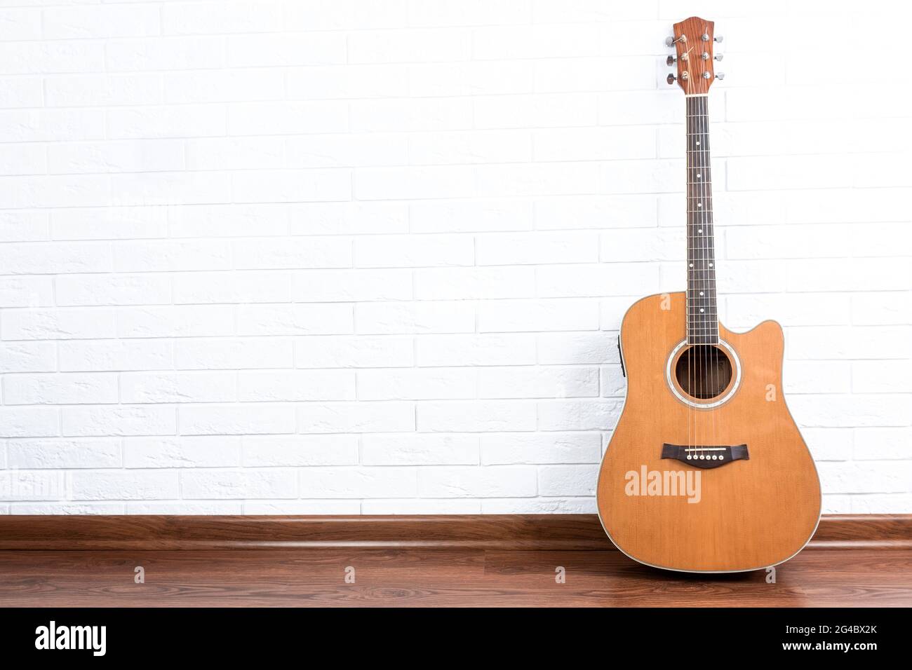 Musical instrument - acoustic guitar with cutaway on a white brick wall ...