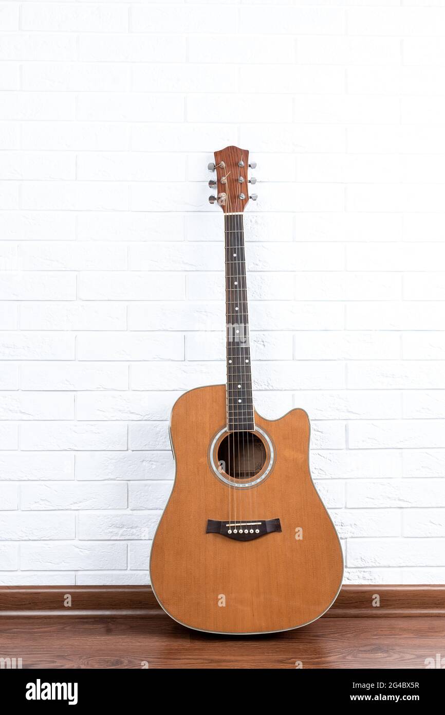 Musical instrument - acoustic guitar with cutaway on a white brick wall ...