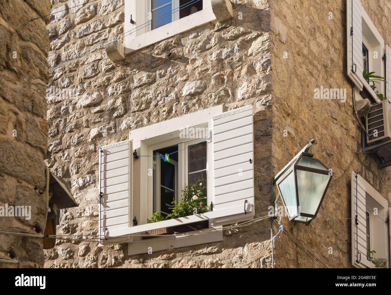 A fragment of the stone house with wooden window with white open ...