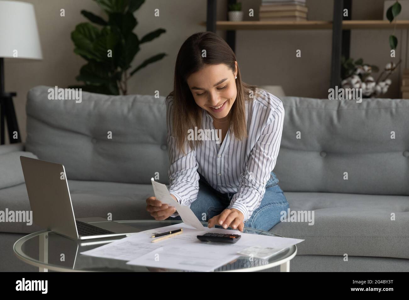 Happy young woman calculating expenditures at home Stock Photo - Alamy