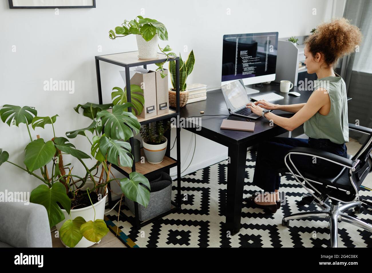 Programmer sitting on her workplace and working with software on laptop ...