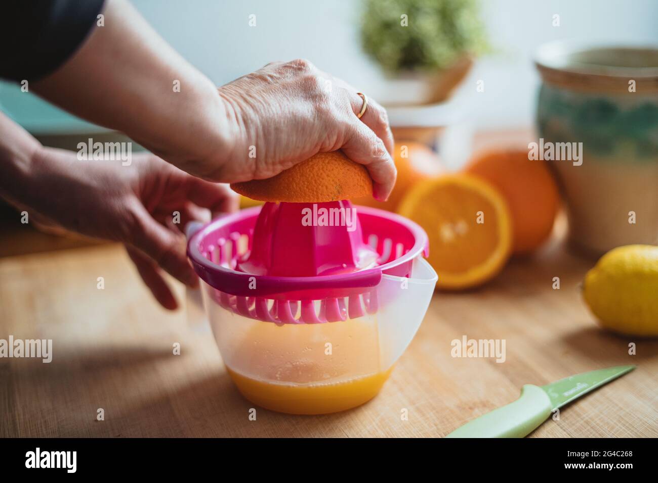 Woman squeezing orange to make orange juice in the morning (side view ...