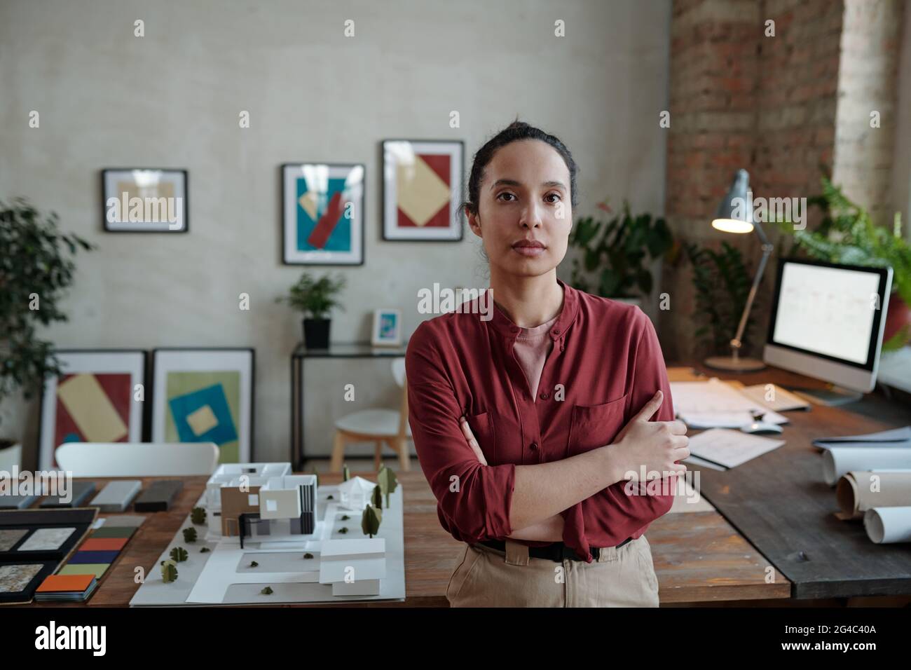 Portrait of serious Hispanic female architect standing with crossed ...