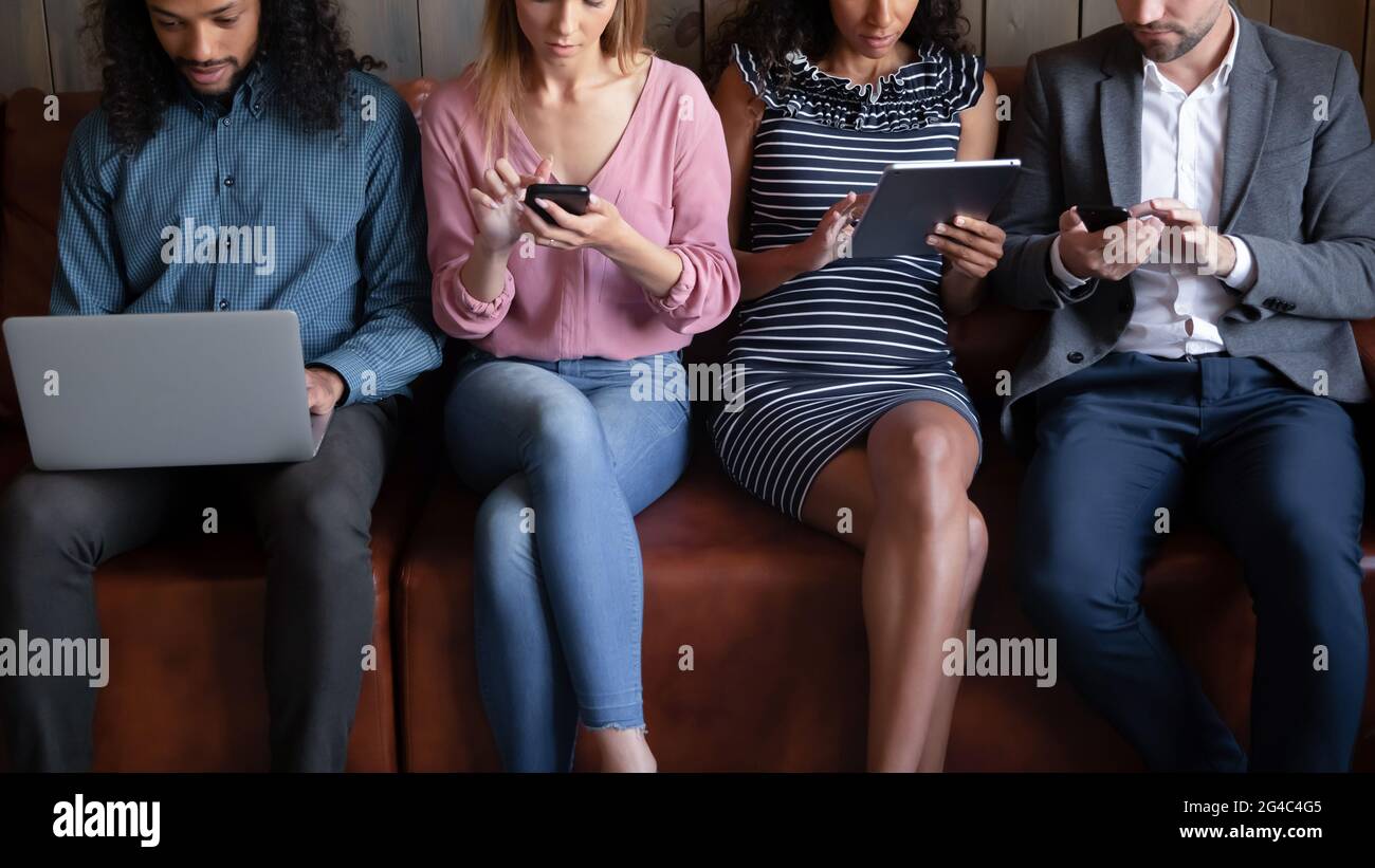 Four diverse young people using different gadgets Stock Photo - Alamy