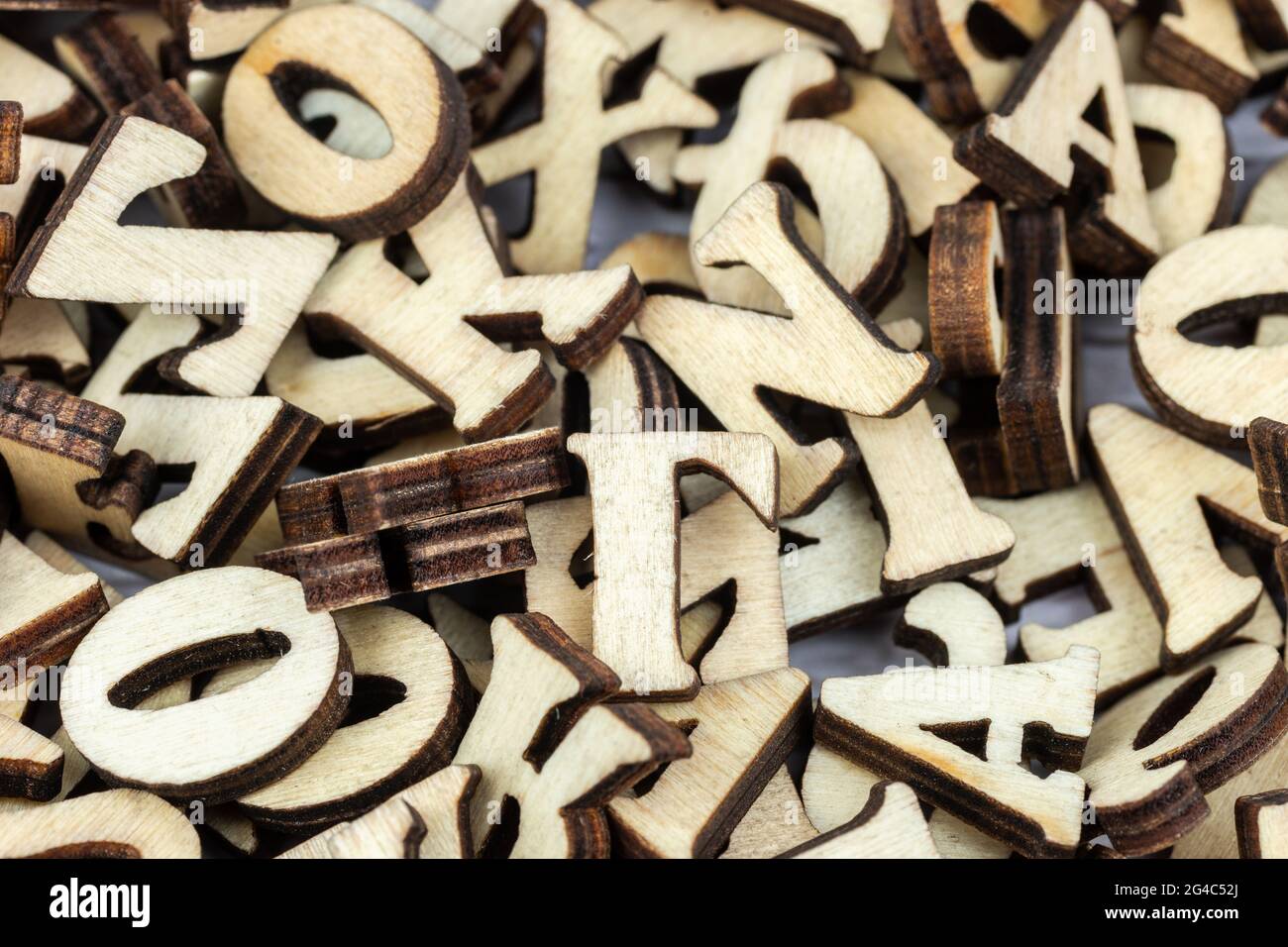 A stack of small wooden letters on a dark table. Letters outlines for ...