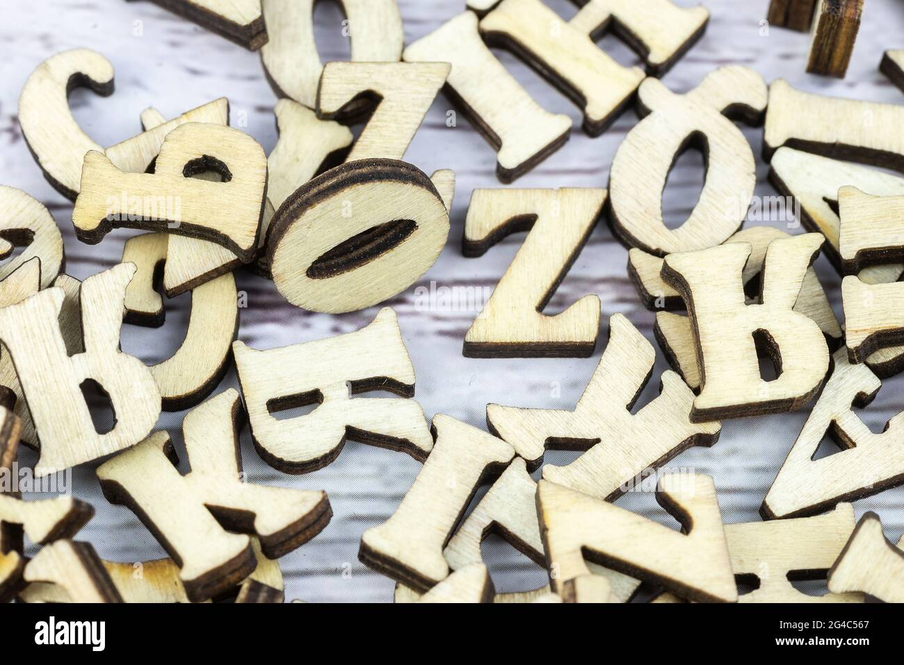 A stack of small wooden letters on a dark table. Letters outlines for ...