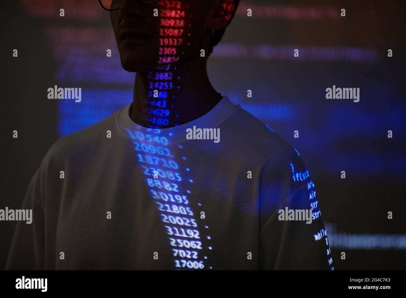 Young computer hacker with computer code reflecting on his face working ...
