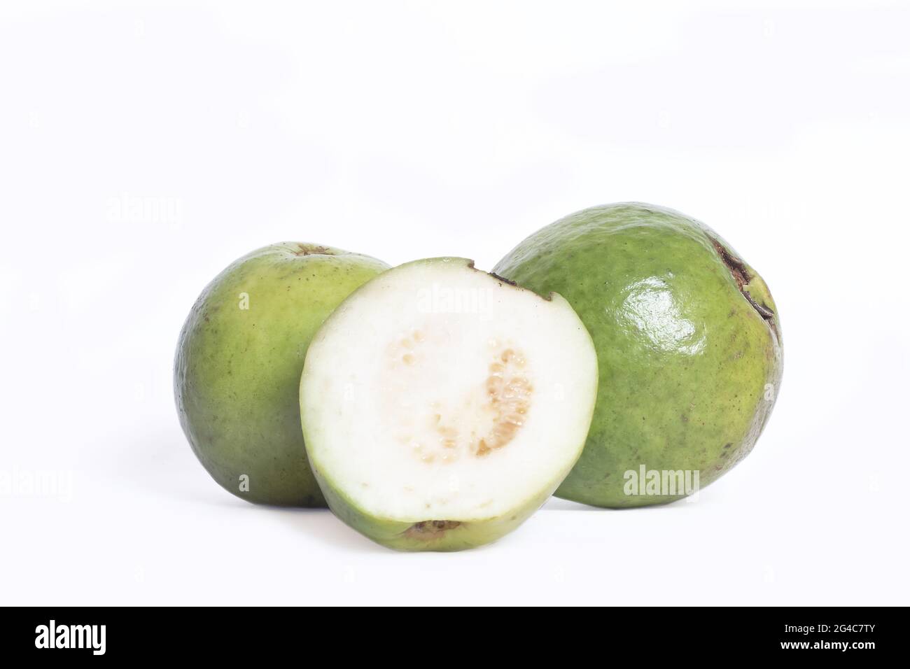 A couple of fresh, full guavas and half-cut guava with a white ...