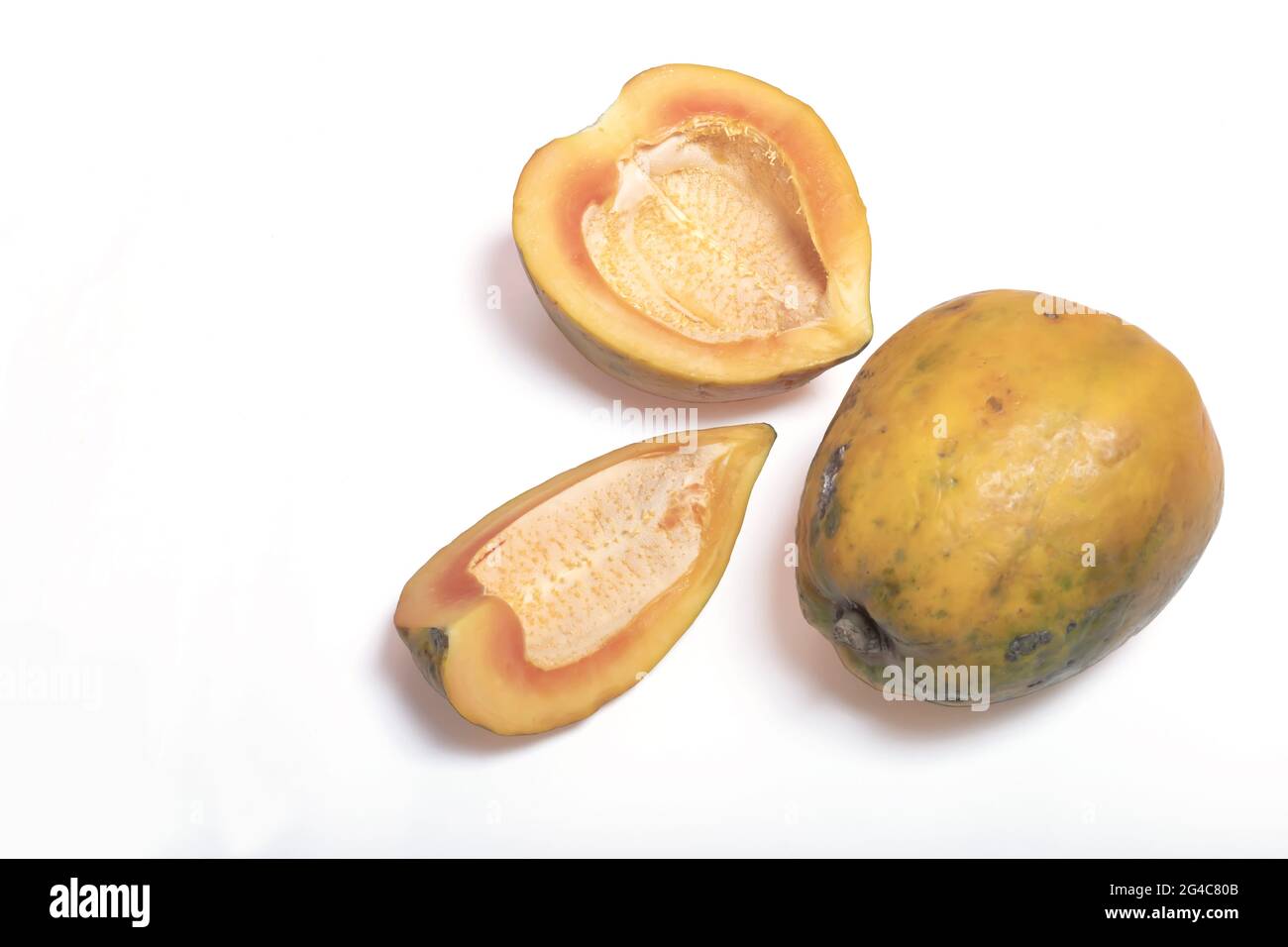 A top view of a sliced mango next to a full one with a white background ...