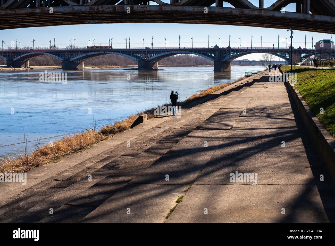 A closeup shot of a person walking on the sidewalk near the river under ...