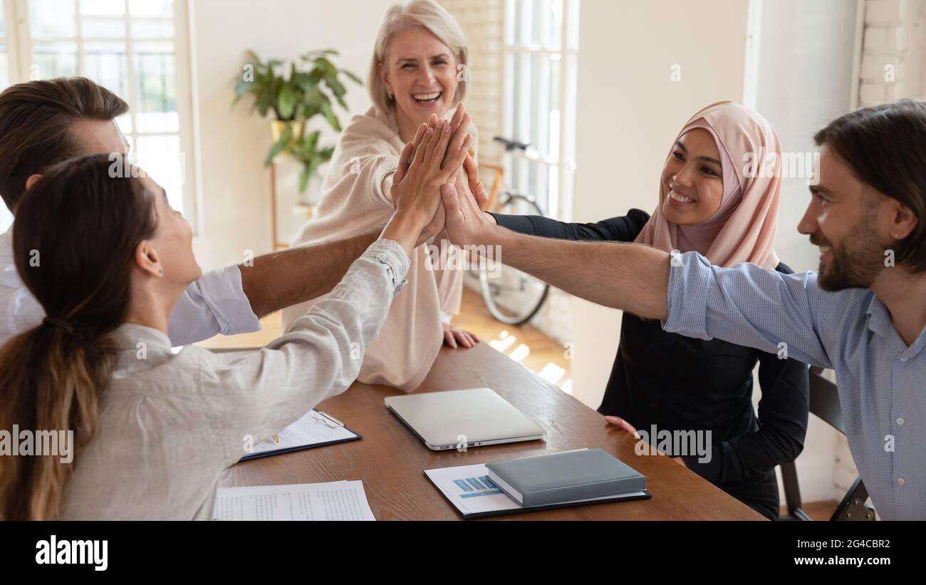 Happy multiethnic employees group giving high five at meeting Stock ...