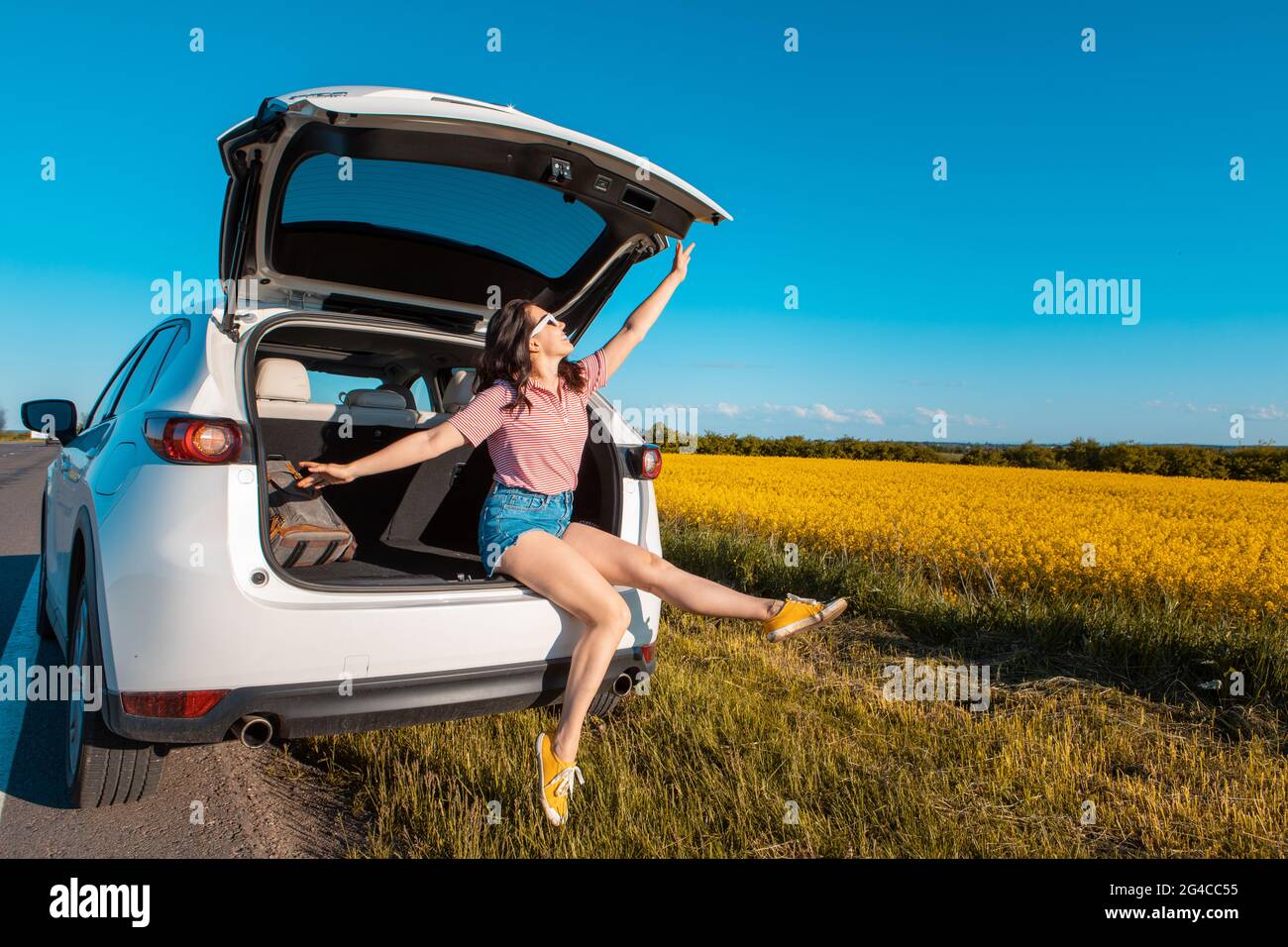 smiling pretty woman sitting in suv car trunk on sunset looking at farm ...