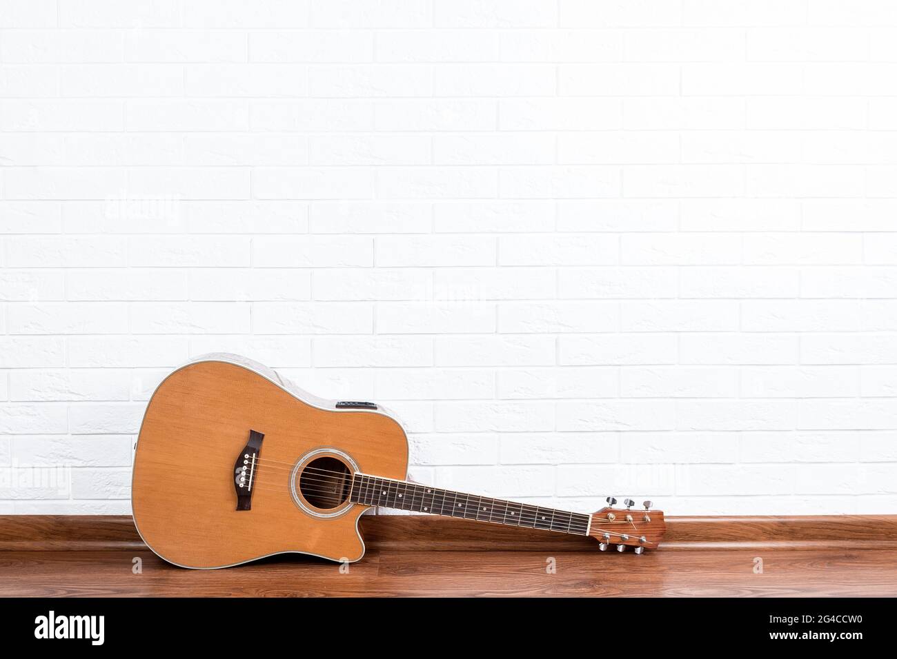 Musical instrument - acoustic guitar with cutaway on a white brick wall ...