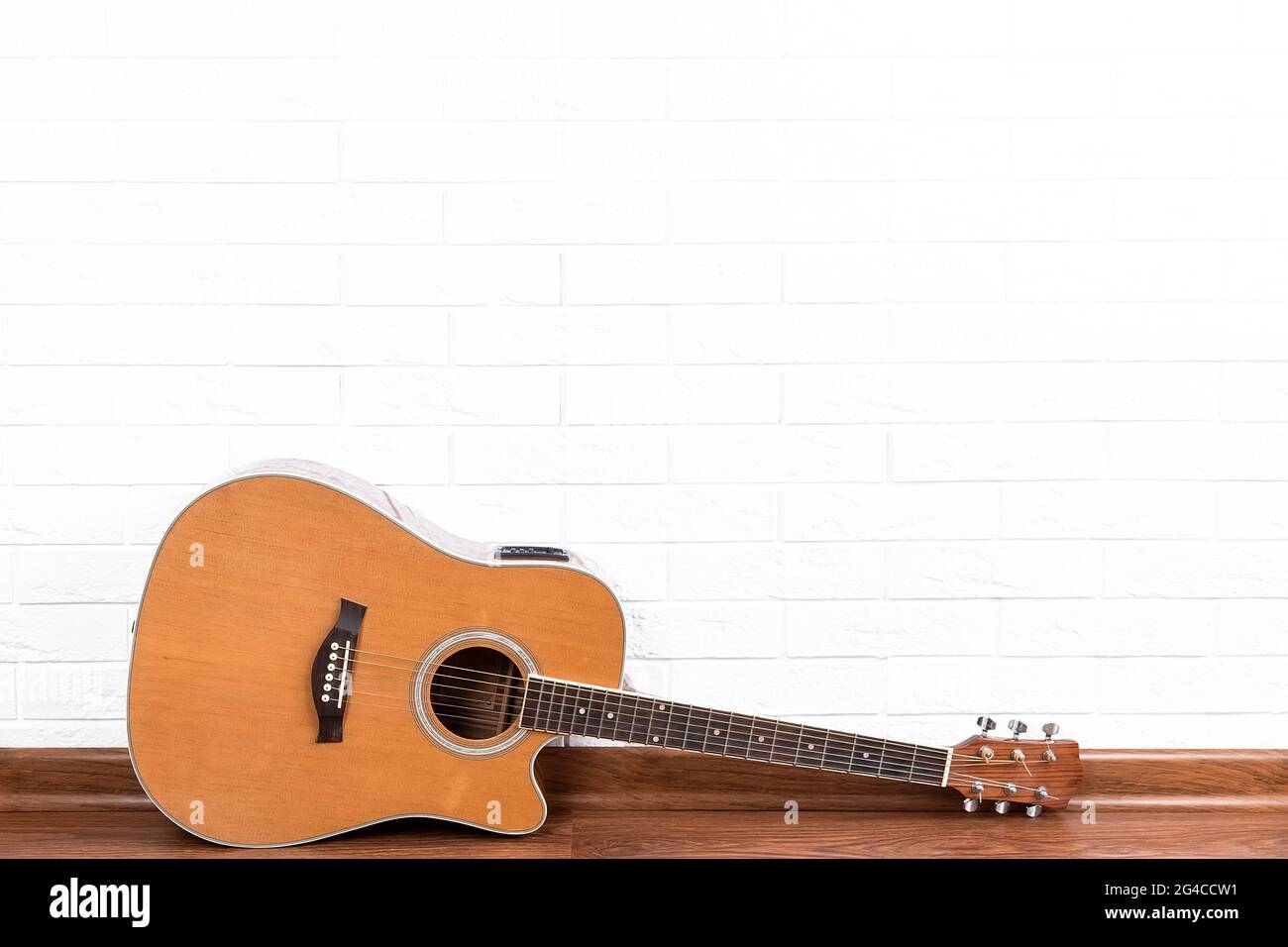 Musical instrument - acoustic guitar with cutaway on a white brick wall ...