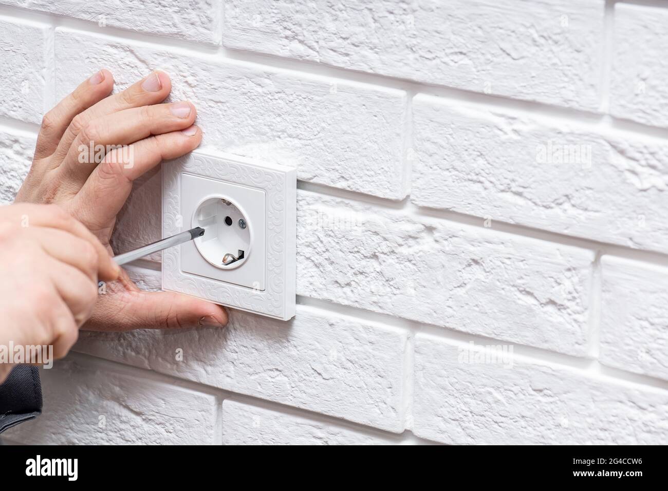 Electrician mounting electric sockets on the white wall indoors Stock ...