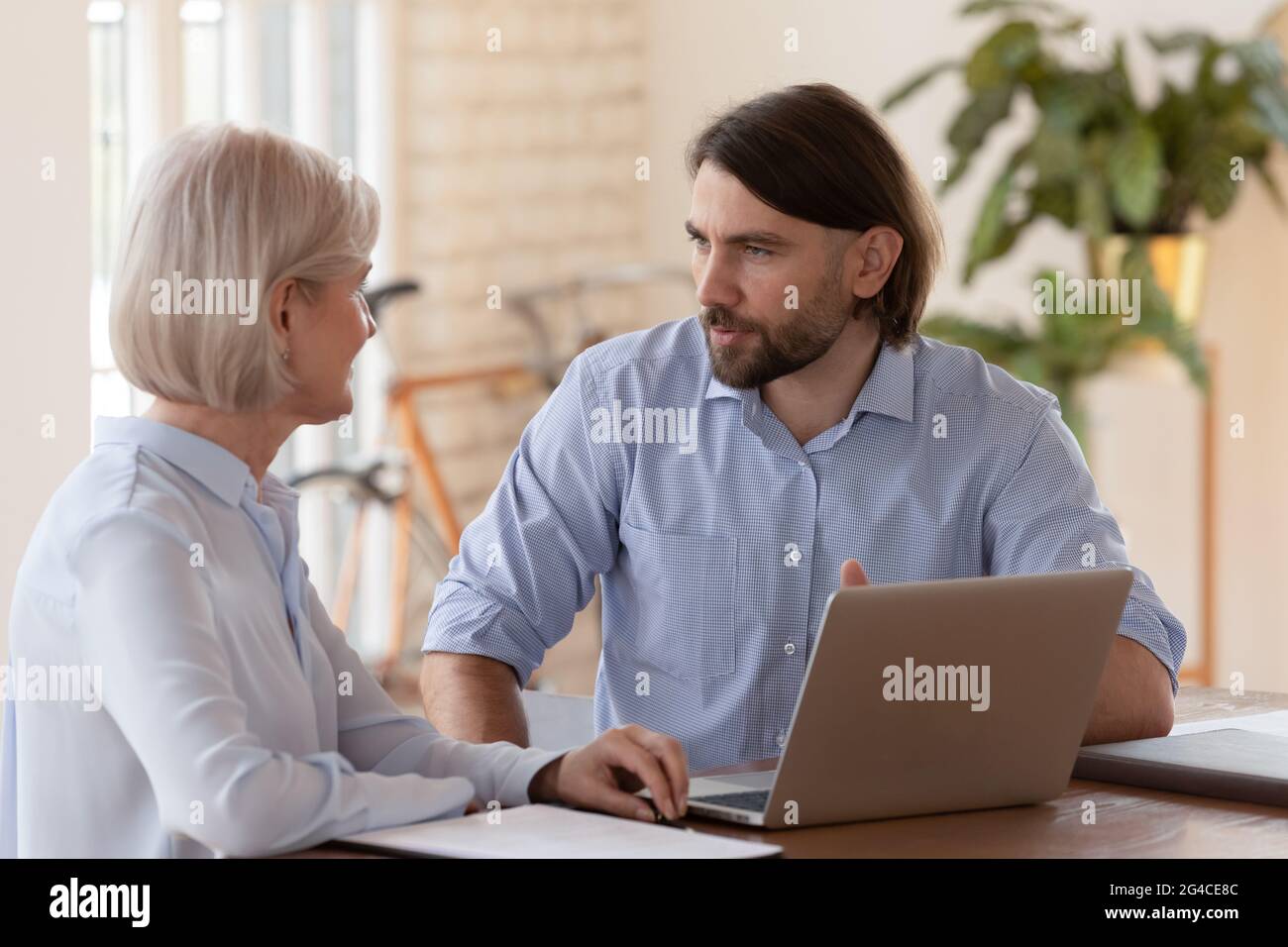 Helpful team leader helping mature employee with corporate software ...