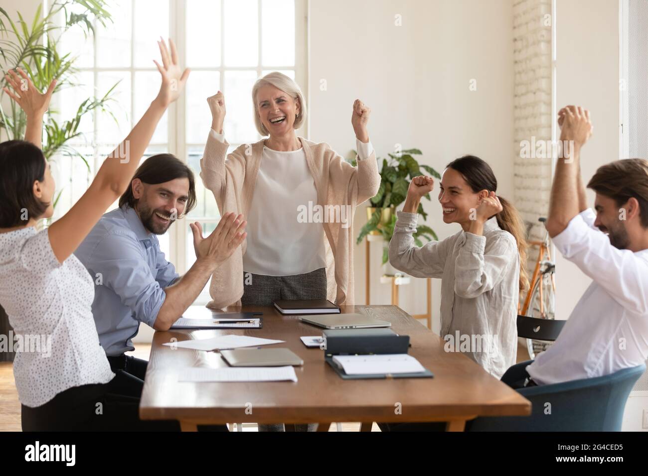Excited diverse employees with middle aged leader celebrating success ...