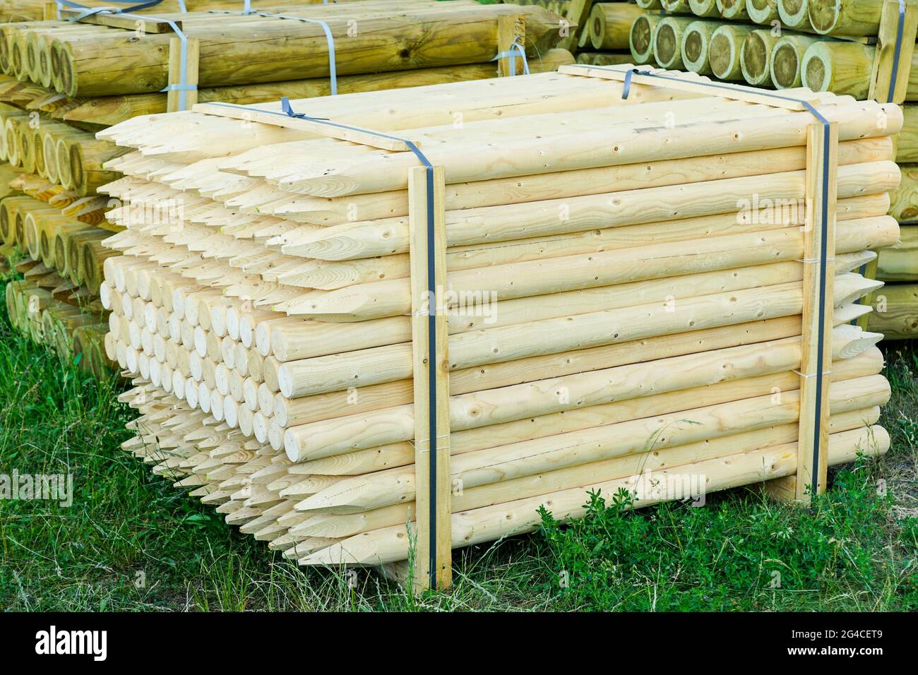 pallet with long round natural wooden fence posts with a sharpened tip ...