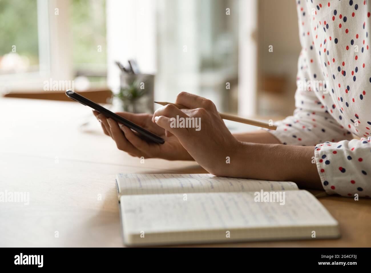Close up woman holding smartphone, taking notes in notebook Stock Photo ...