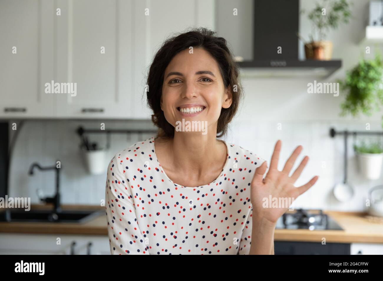 Head shot portrait of smiling woman waving hand at camera Stock Photo ...