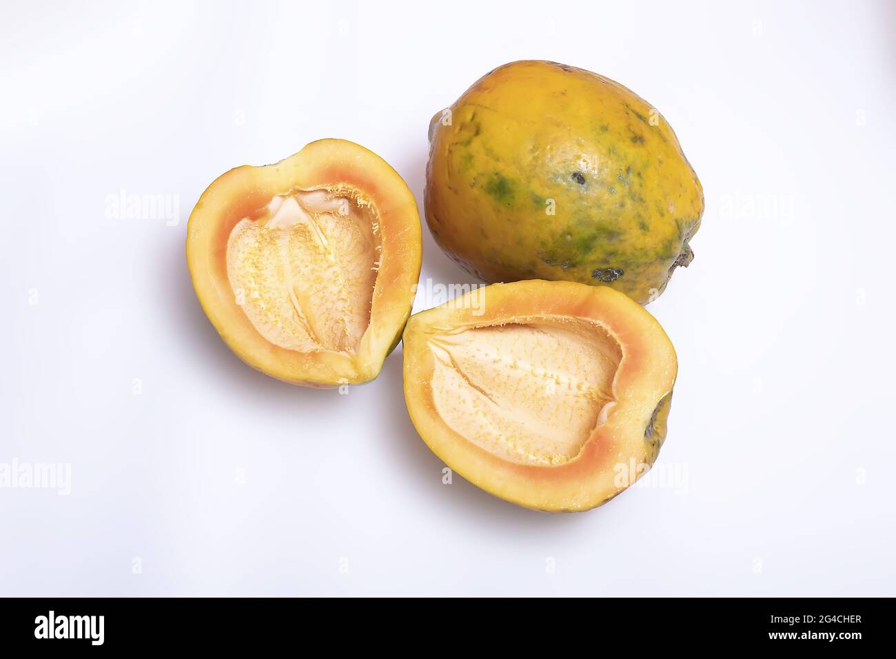 A top view of a half-cut mango and a full mango with a white background ...