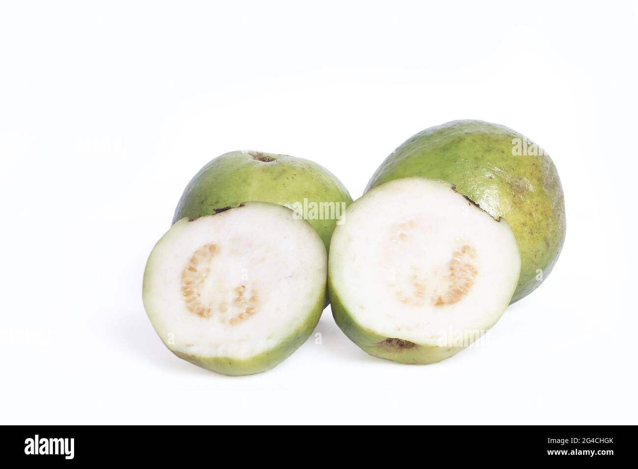 A couple of fresh, full guavas and half-cut guava with a white ...