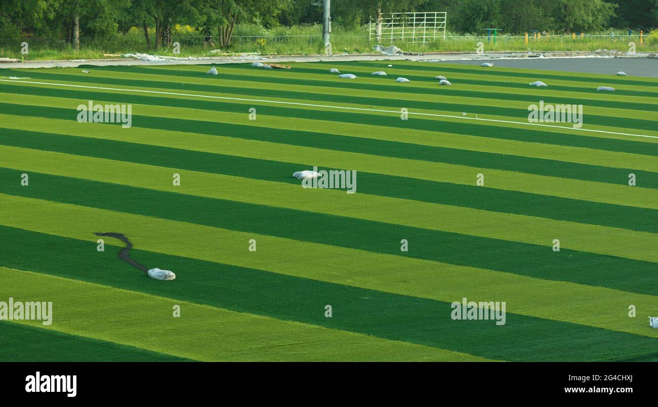 Close-up. Replacing the football surface with a new artificial turf ...