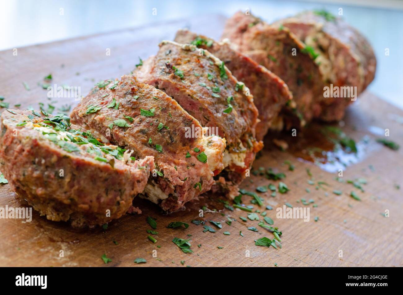 A closeup shot of sliced wrapped burger roll topped with herbs on a ...