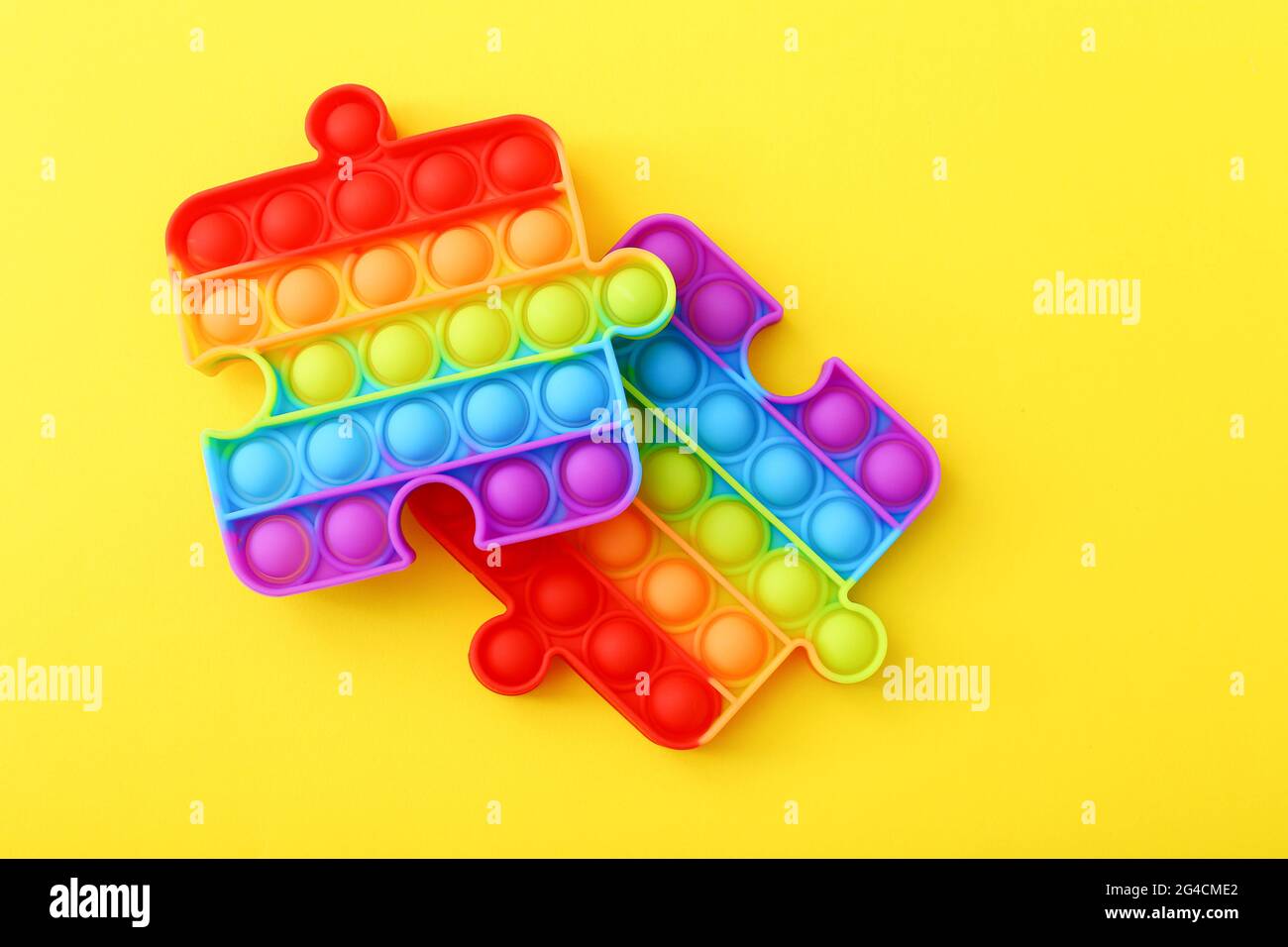 Popit toy in the form of a puzzles on a yellow background. Multicolored ...
