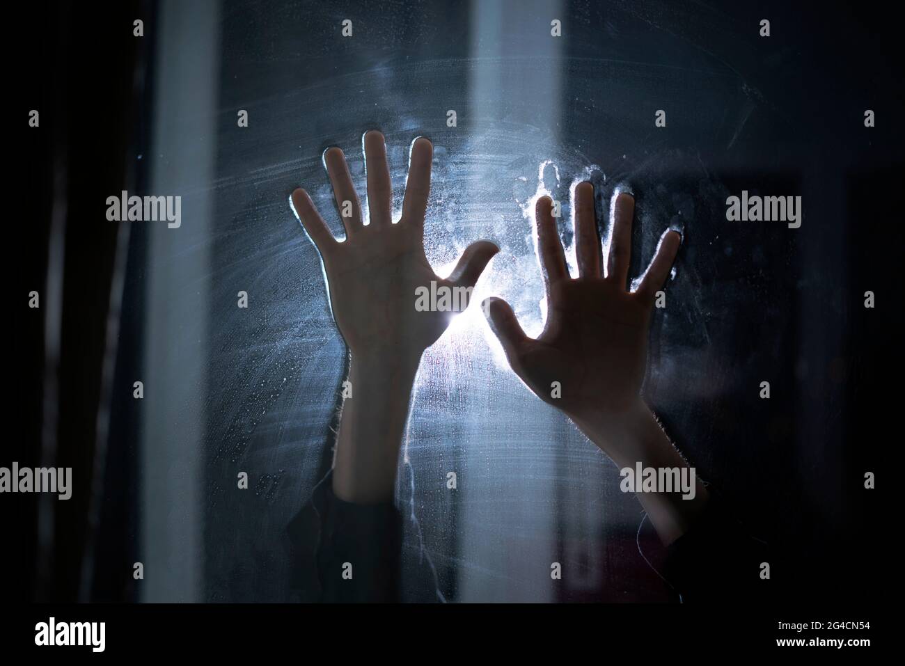 creepy horror scene, person's hands in the dark behind the glass ...