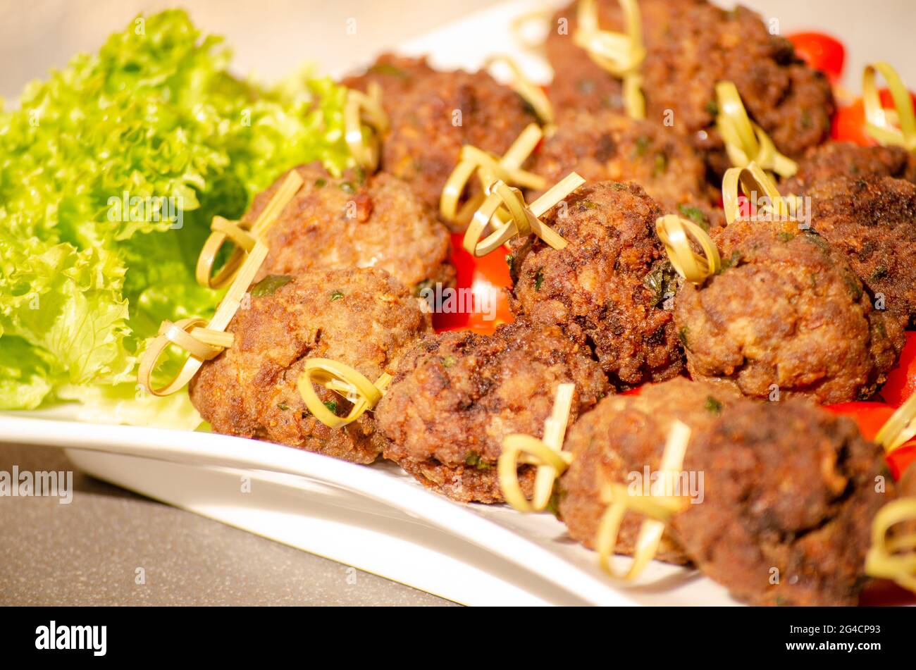 A closeup shot of meatballs served with small tomatoes and lettuce leaf ...