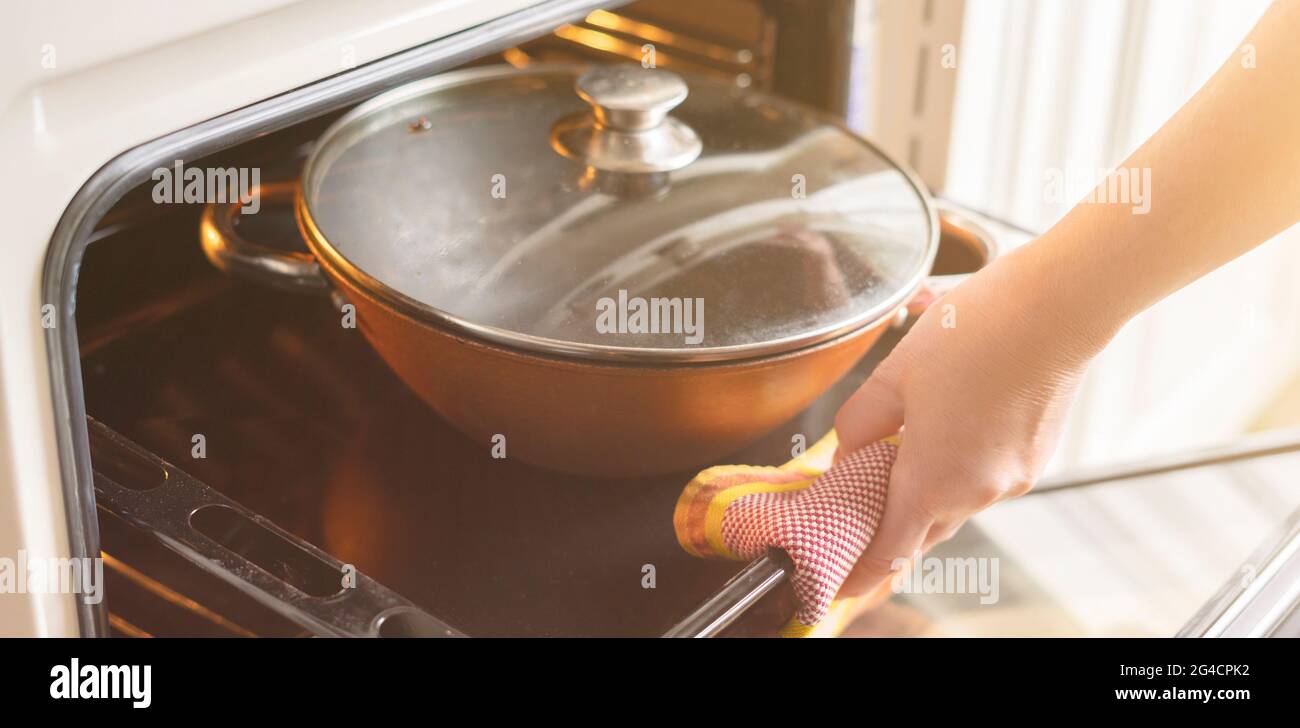 close up woman hands open the oven and take out fresh cooked food at ...