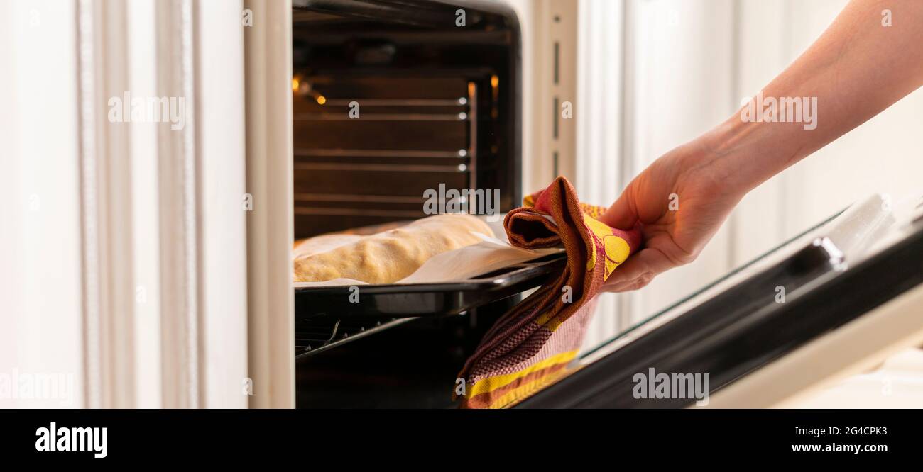close up woman hands open the oven and take out fresh cooked food at ...