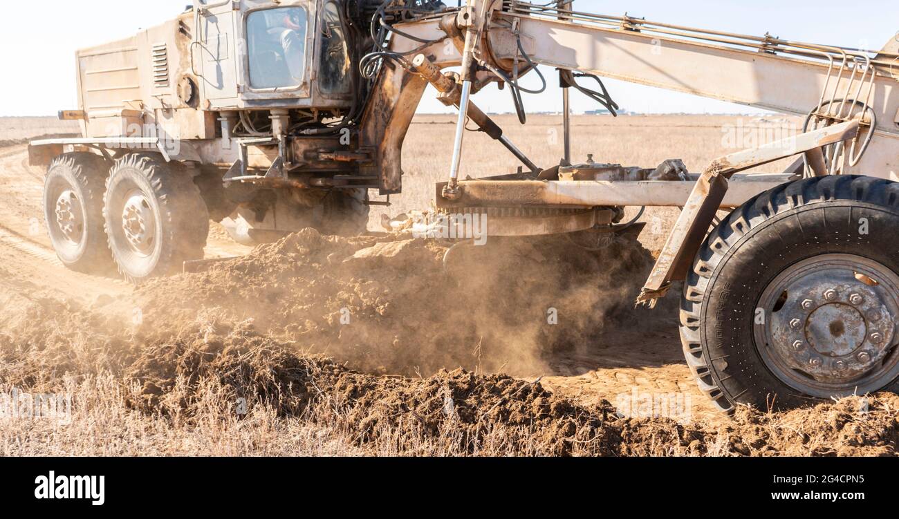close up grader scoop dig the dirt on summer day, making a parapet ...