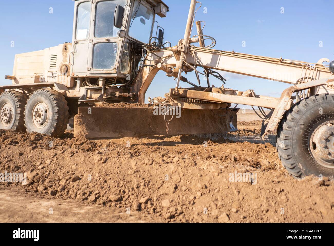 close up grader scoop dig the dirt on summer day, making a parapet ...
