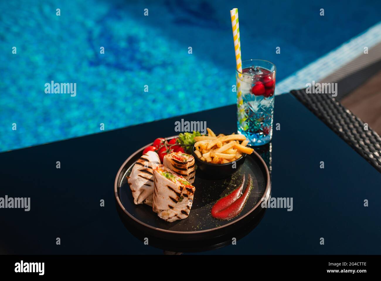 Chicken in a tortilla with cherry tomatoes and french fries placed by ...