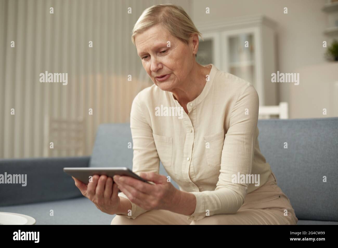 Senior old woman using digital tablet at home. The use of technology by ...