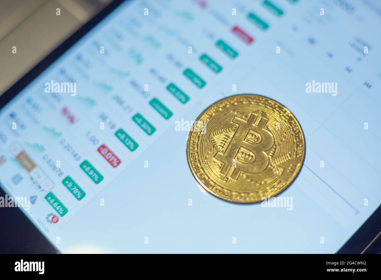 A tablet on which cryptocurrency rates are displayed. There is a gold ...