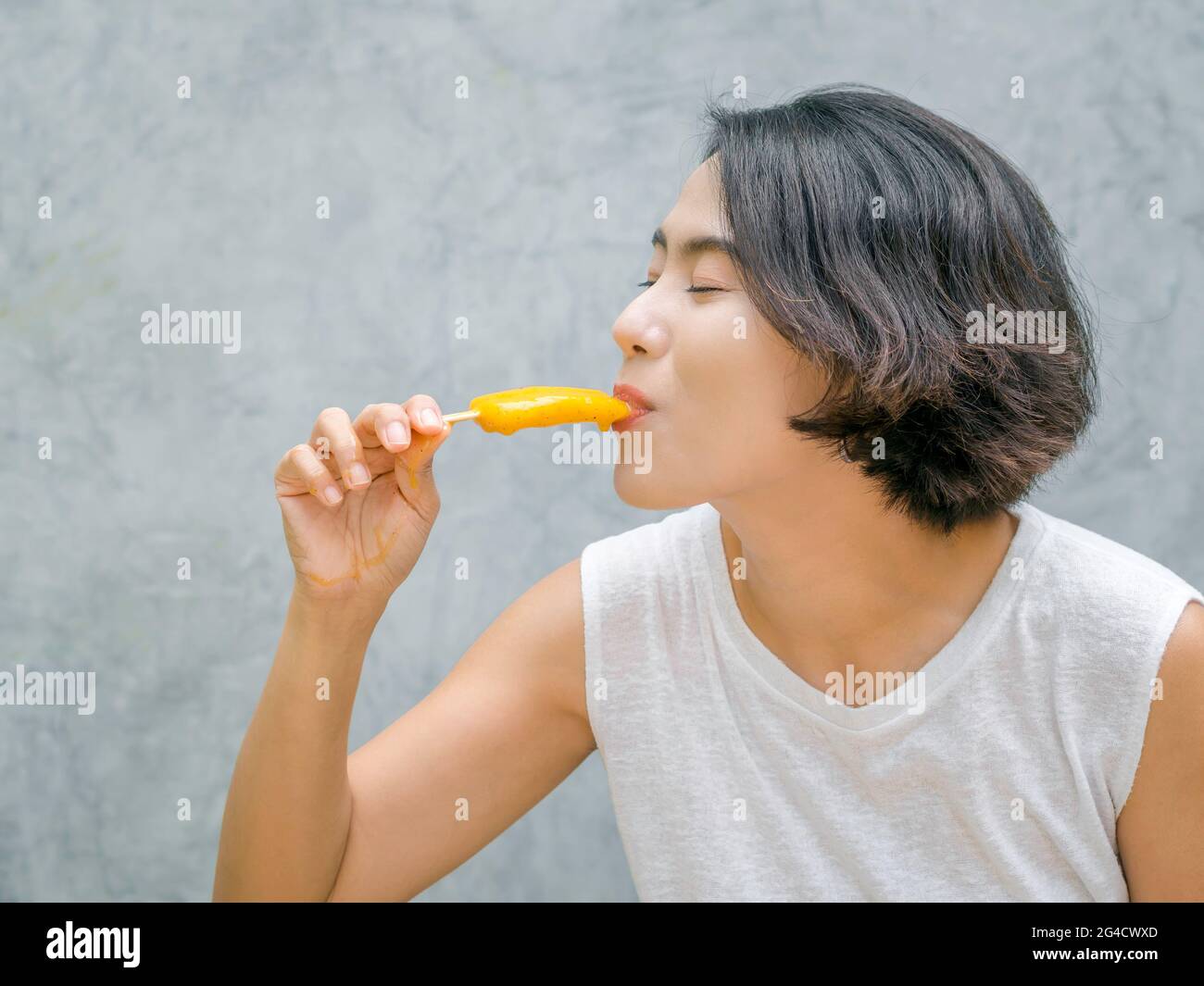 Woman eating popsicles. Happy beautiful Asian woman wearing casual ...