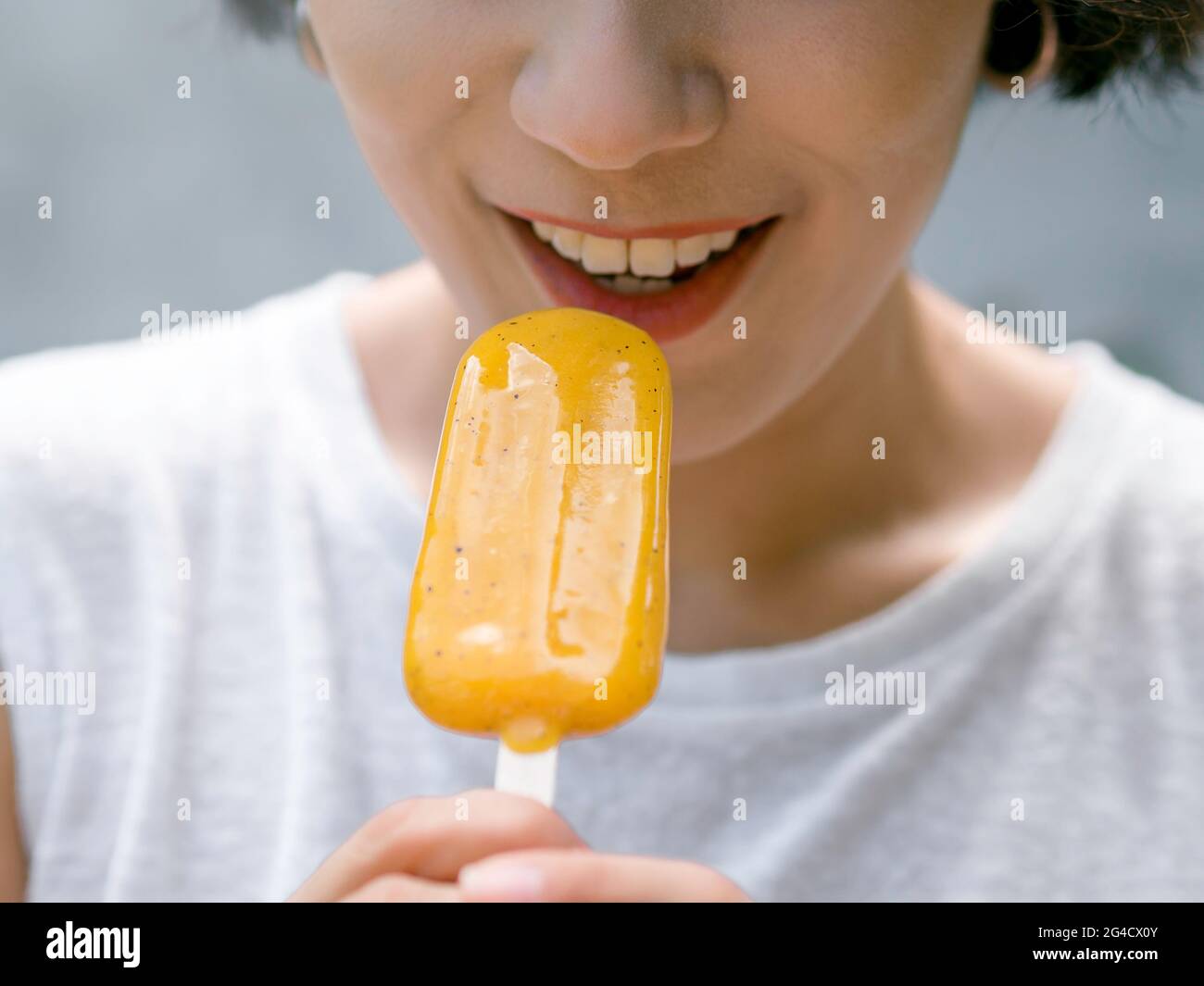 Close up yellow popsicle in beautiful happy Asian woman’s hand wearing ...