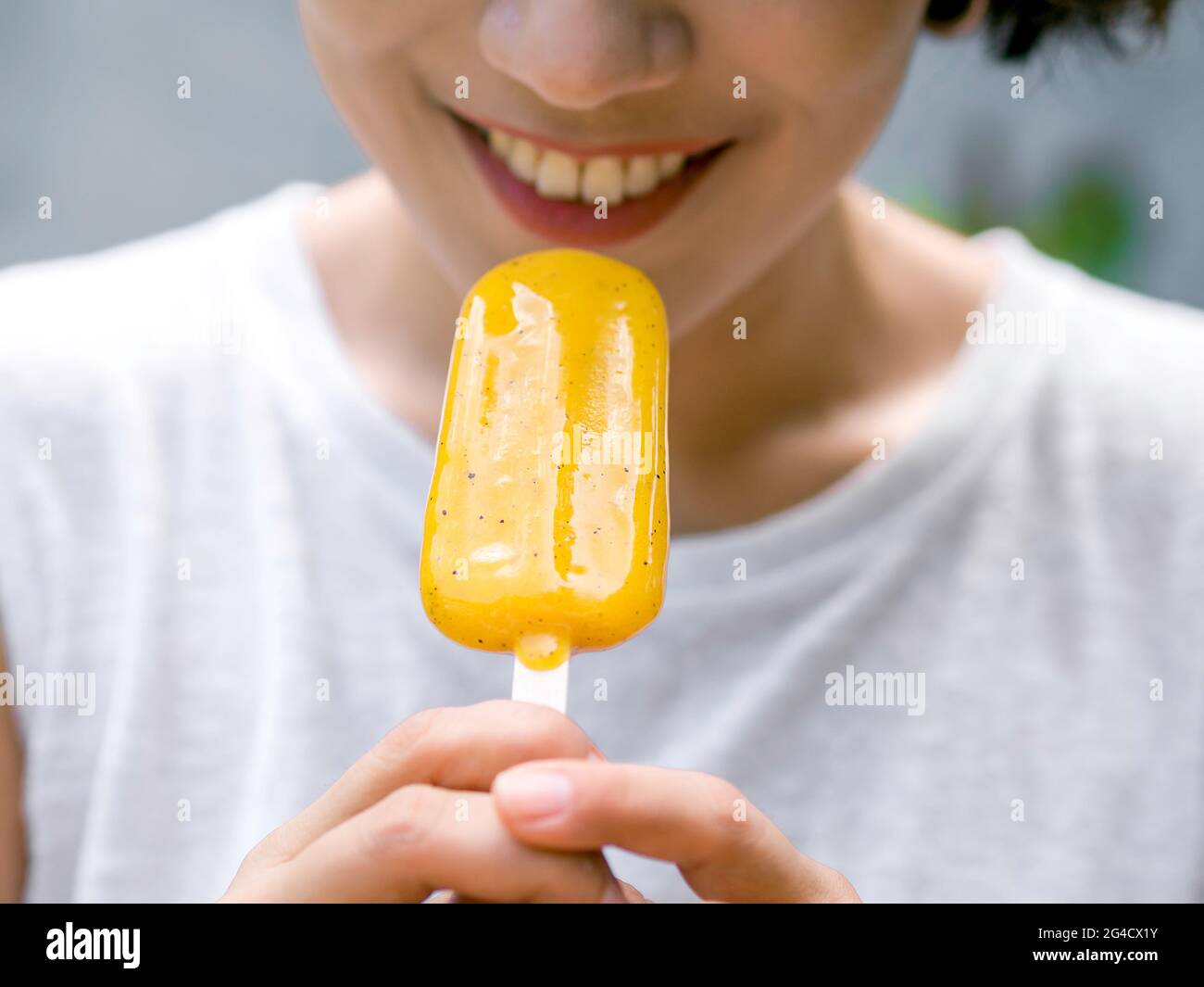 Close up yellow popsicle in beautiful happy Asian woman’s hand wearing ...