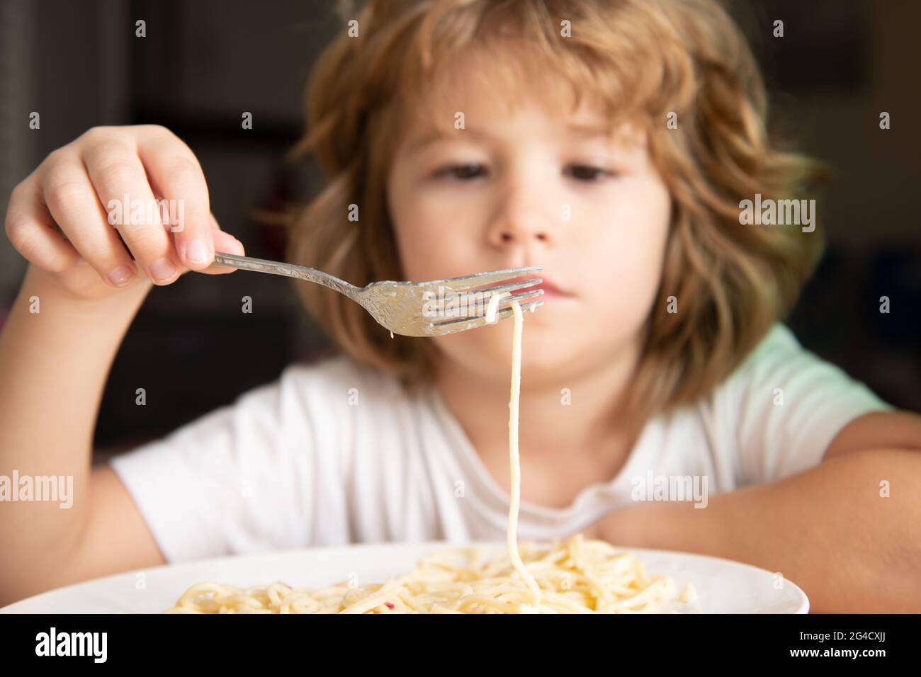 Portrait of a cute child boy eating pasta, spaghetti. Close up ...
