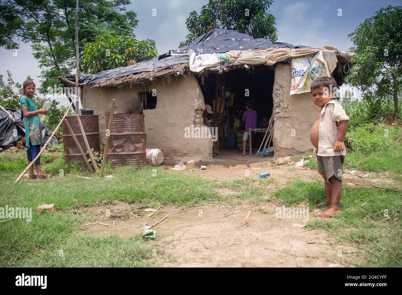 Poor Indian kid standing at the door of a mud house in the rural area ...