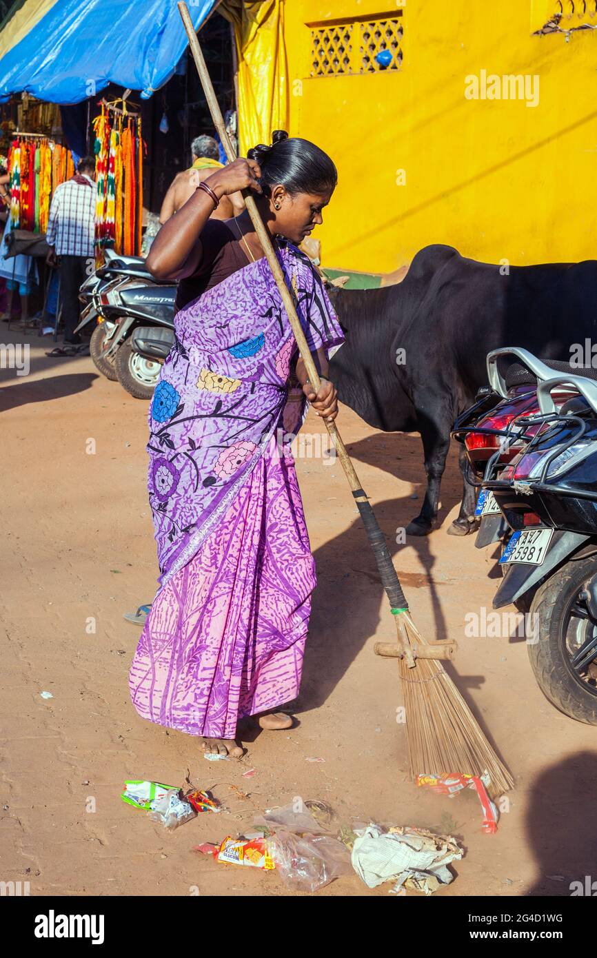 Indian female street cleaner sweeping the dusty streets beside bicycle ...