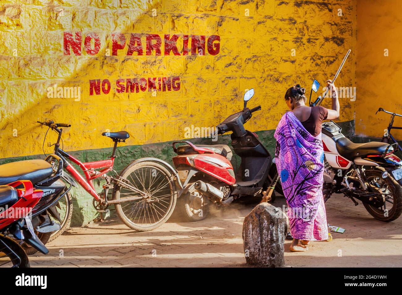 Indian female street cleaner sweeping the dusty streets beside bicycle ...
