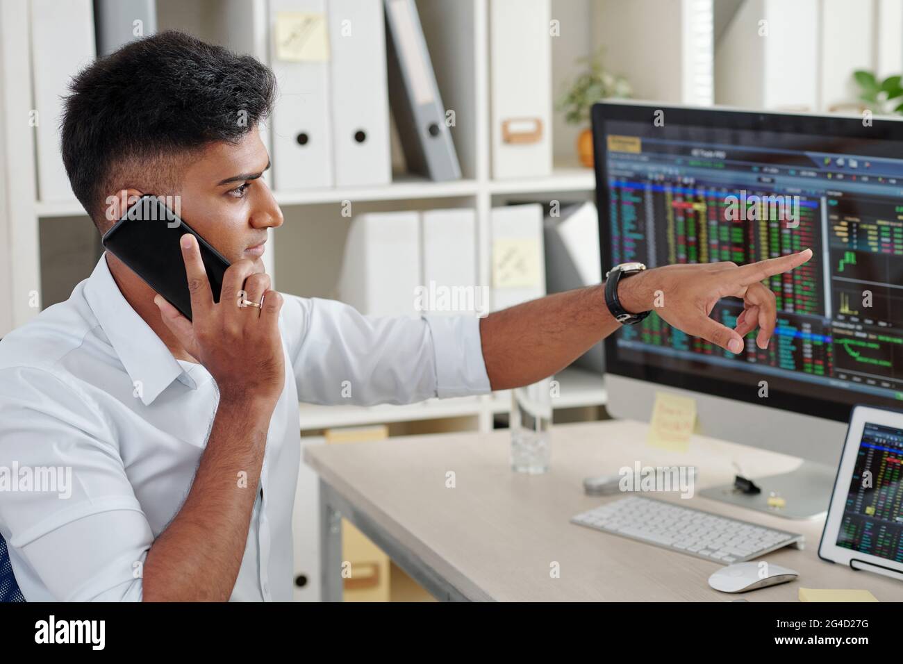Trader pointing at computer screen with stock market data when talking ...