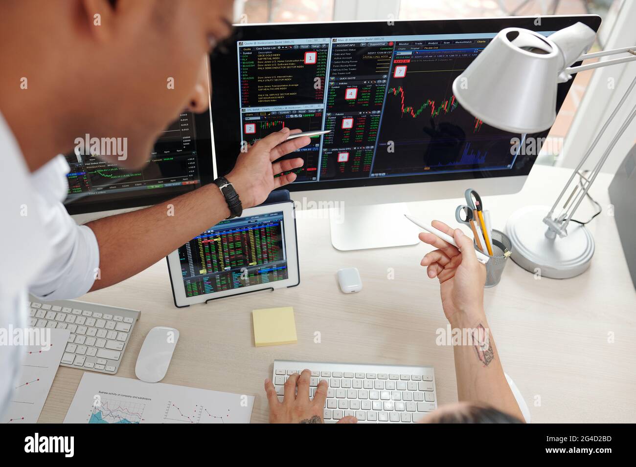 Hands of traders pointing at computer screen, analyzing and discussing ...