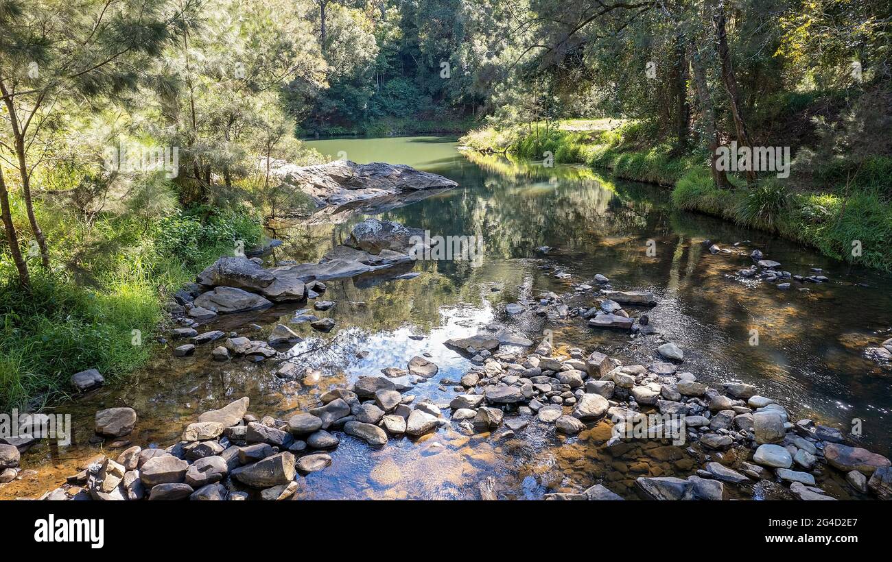 Light and shadows on shallow water flowing over rocks in a creek in the ...