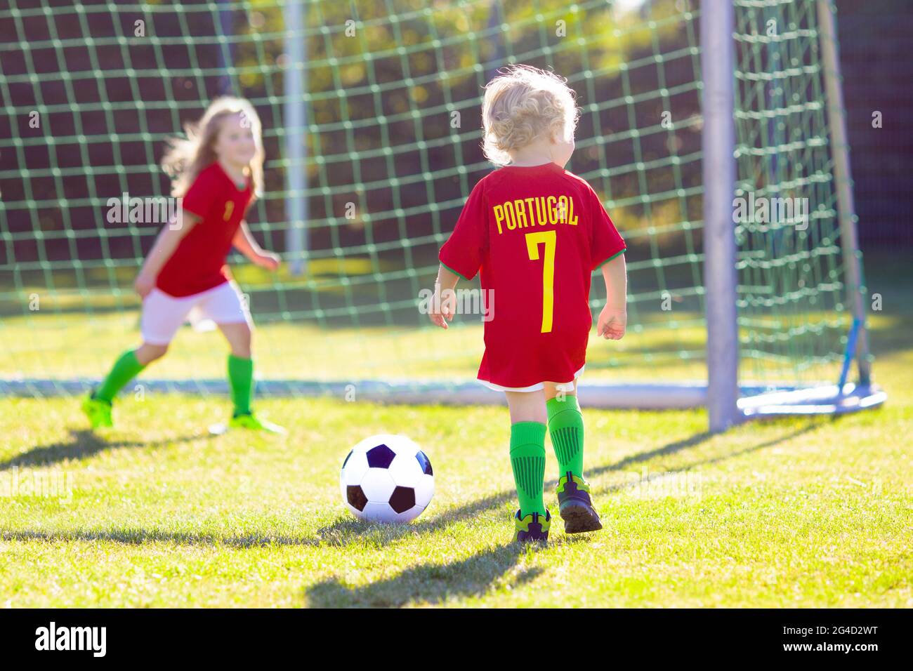 Kids play football on outdoor field. Portugal team fans. Children score ...