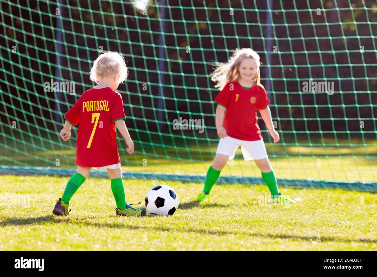 Kids play football on outdoor field. Portugal team fans. Children score ...